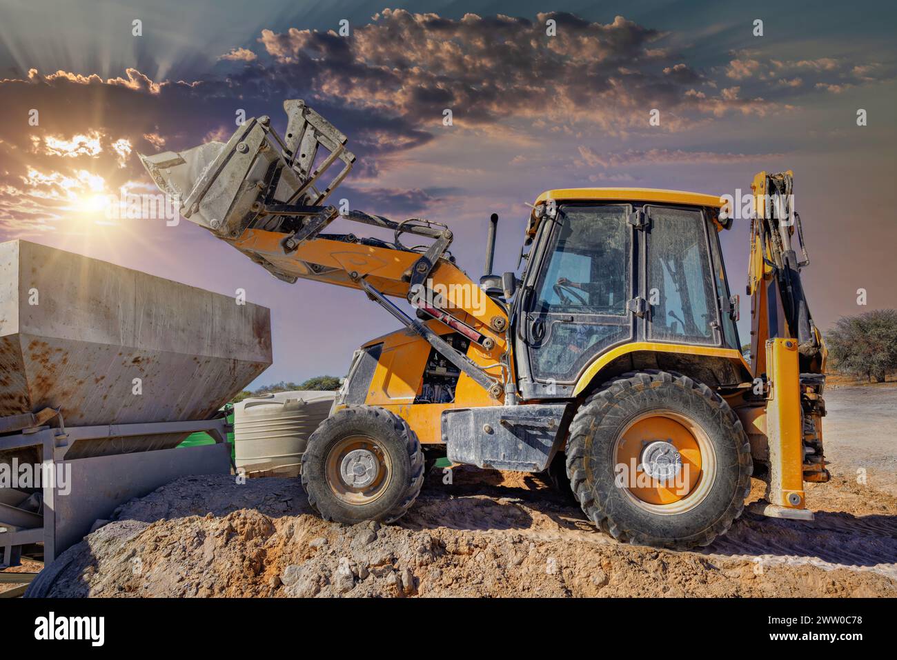 backhoe scooping earth dirt on construction site at sunset, new ...