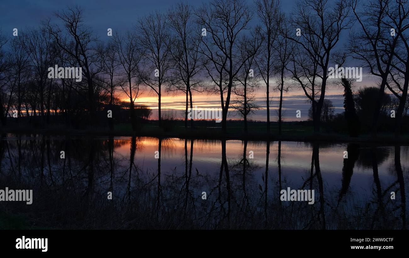 Reflections of trees in water at sunset. The picture is taken at a ...