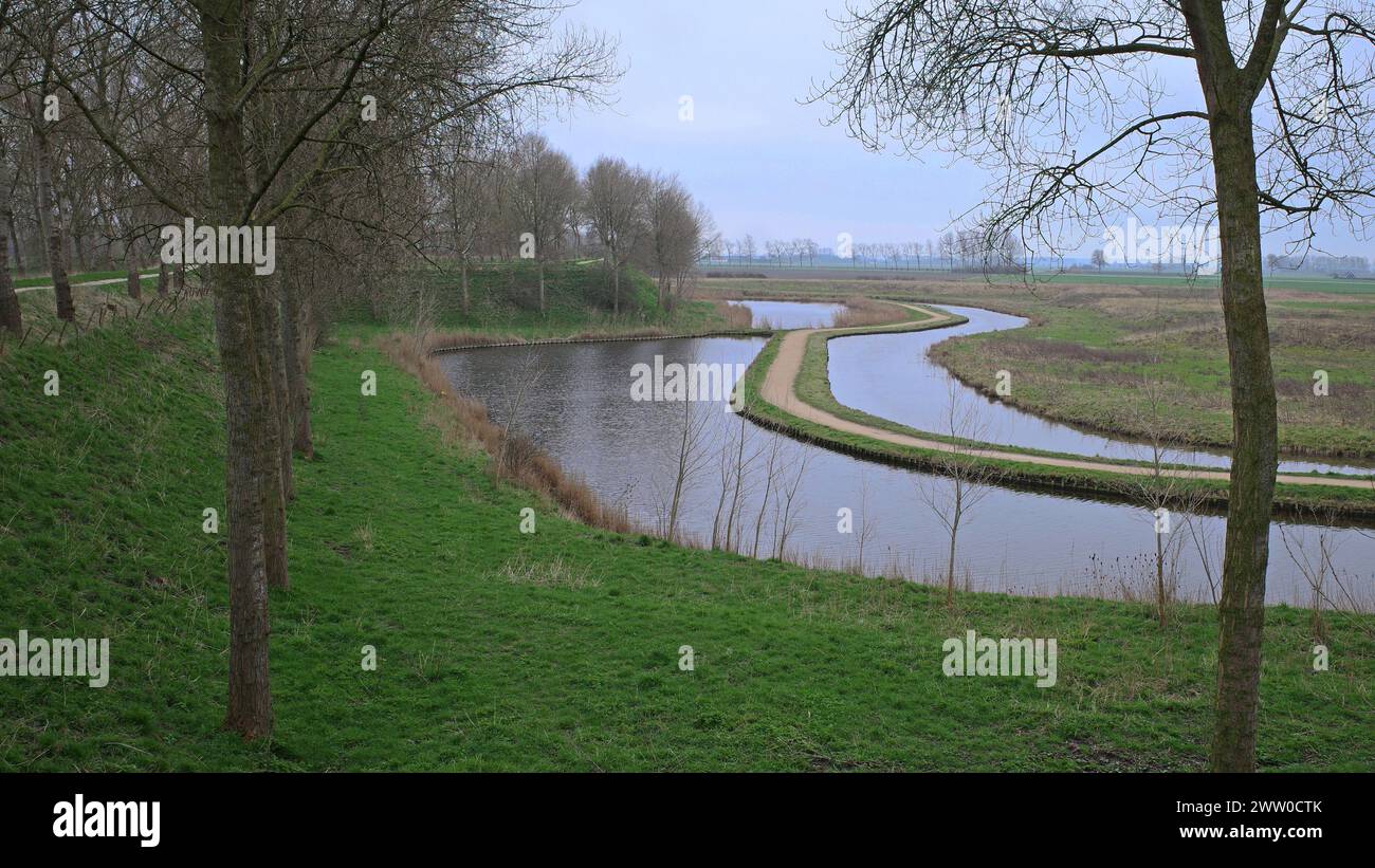 Winter polder view on a canal with a bicycle path created in the middle ...