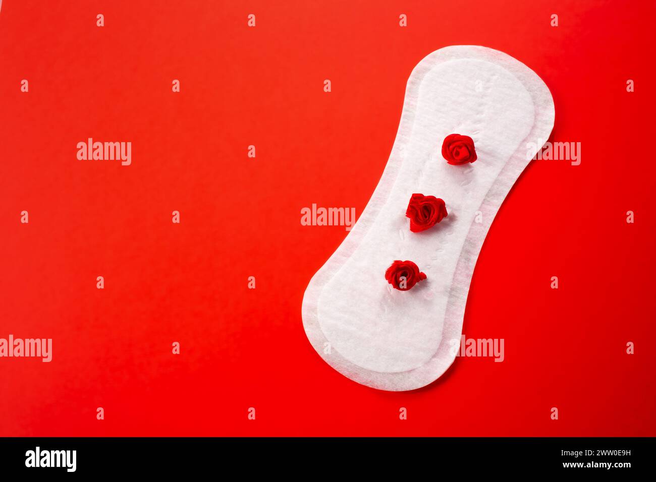 Feminine hygiene pad with red flowers on pink background. First ...