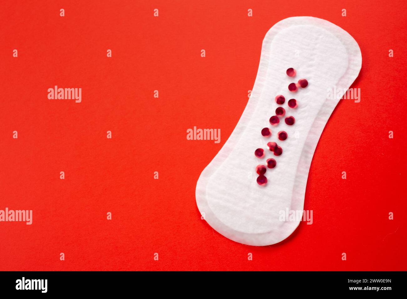 Feminine hygiene pad with red glitter on red background. First ...