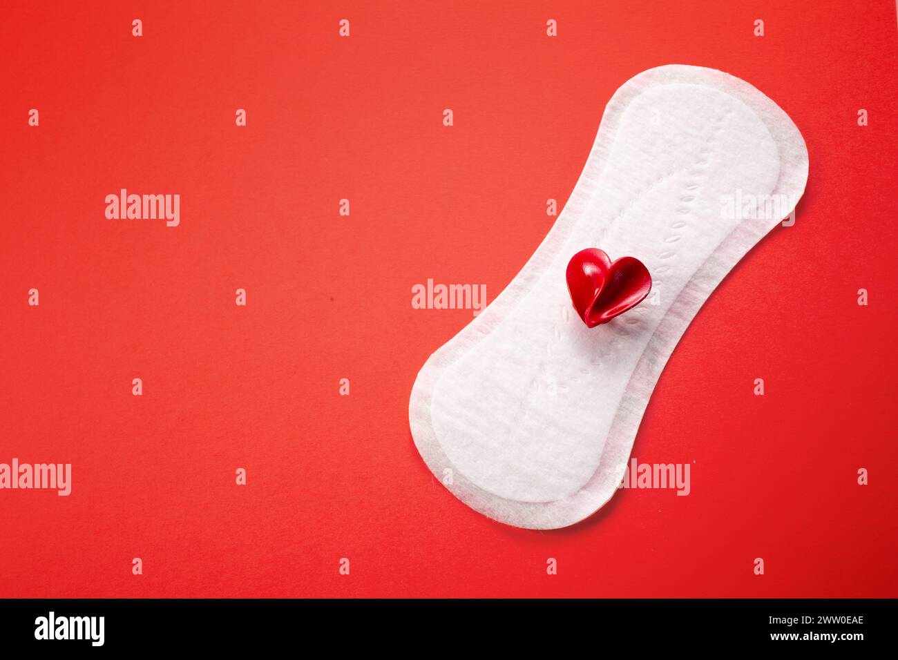 Feminine hygiene pad with red heart on pink background. First menstrual ...