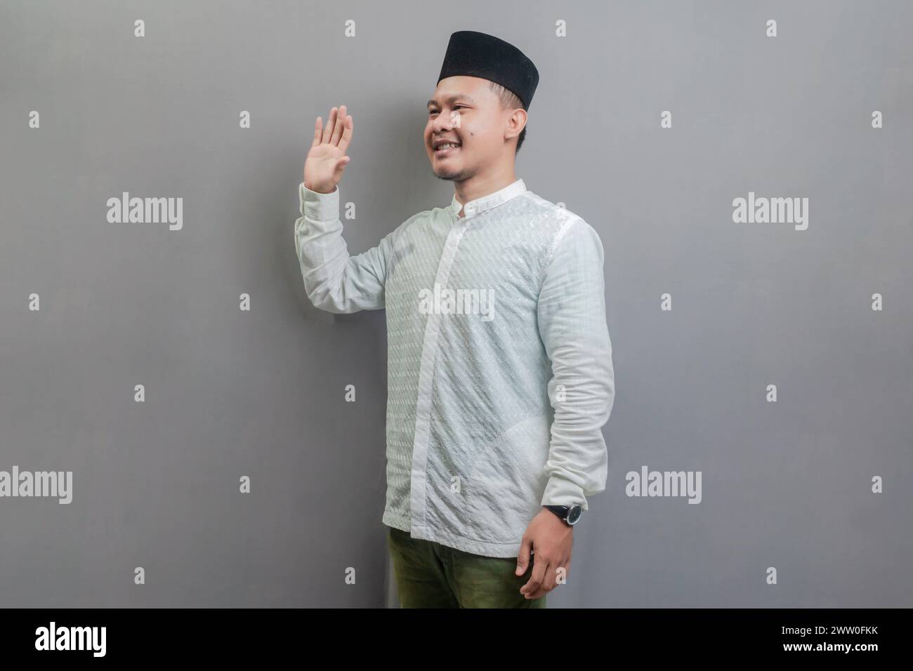 Happy asian muslim man waiving saying hello, friendly welcome gesture ...
