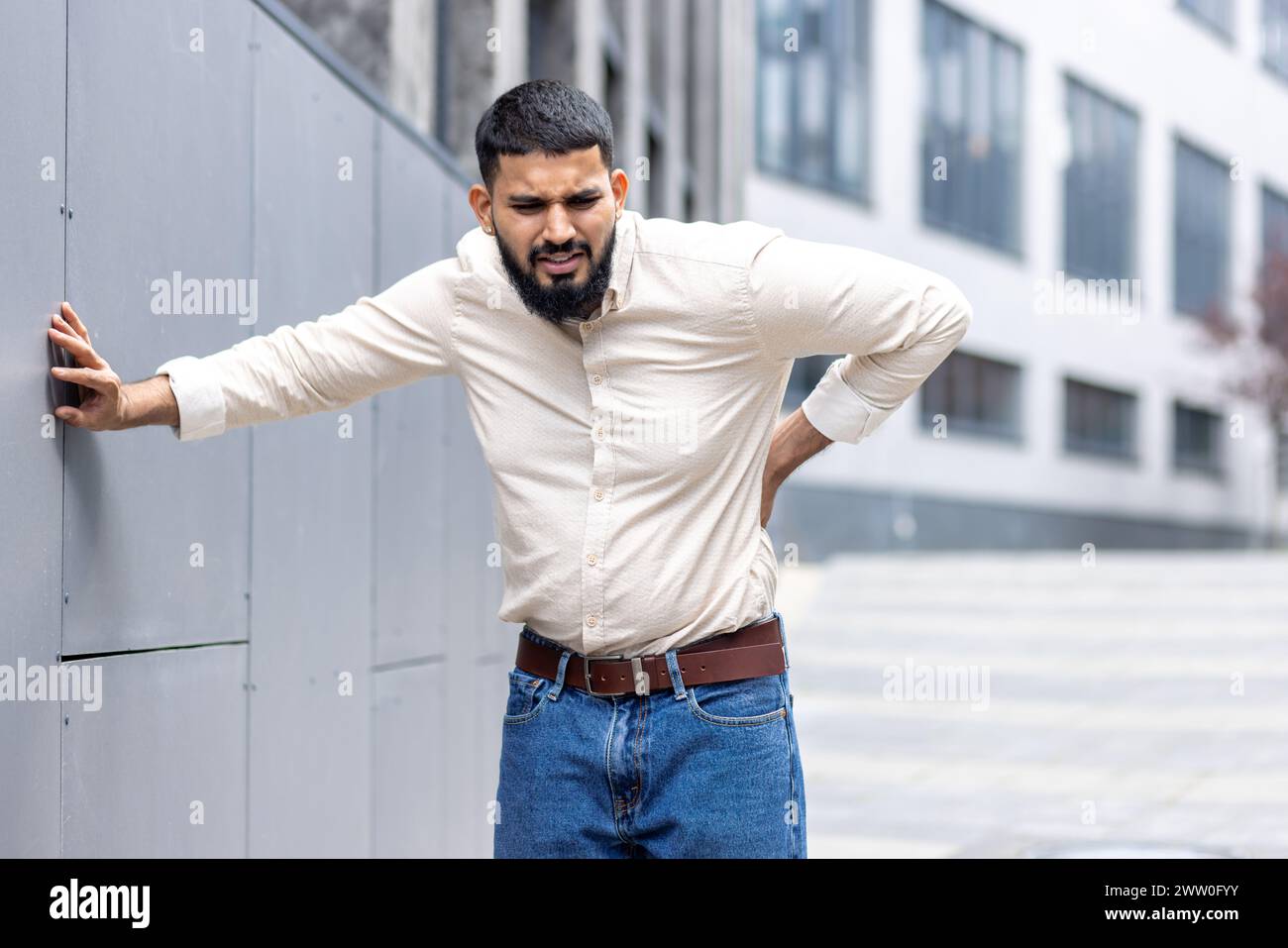 A tired Muslim man is standing outside leaning against the wall of the ...