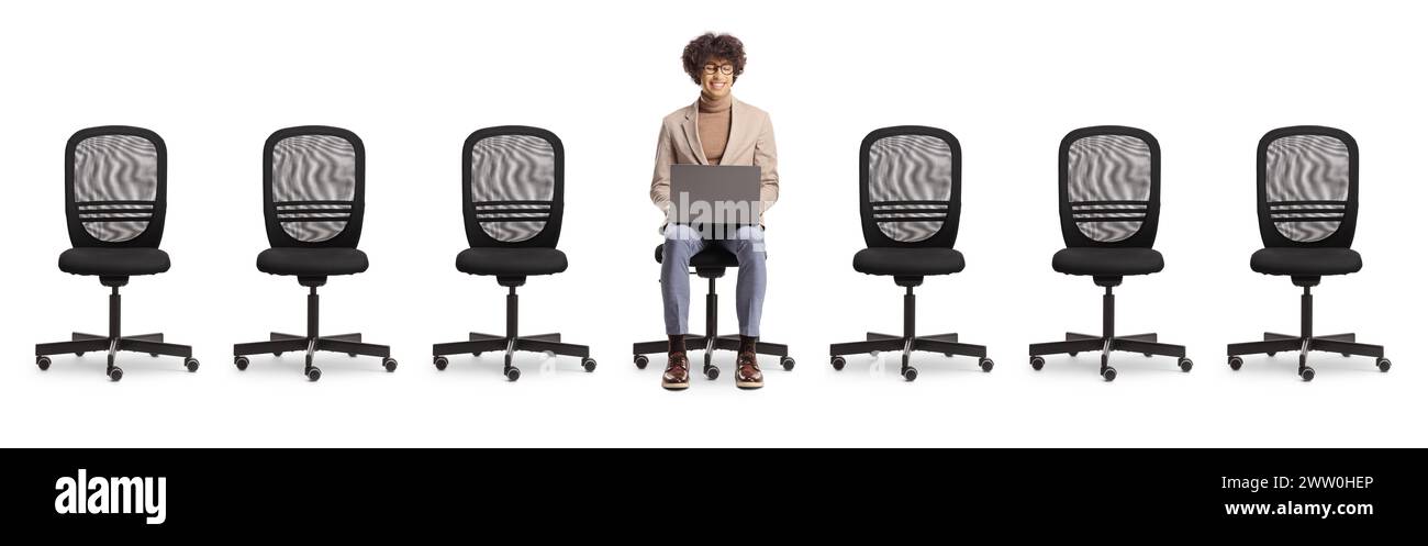 Office chairs and a young man sitting and using a laptop computer ...