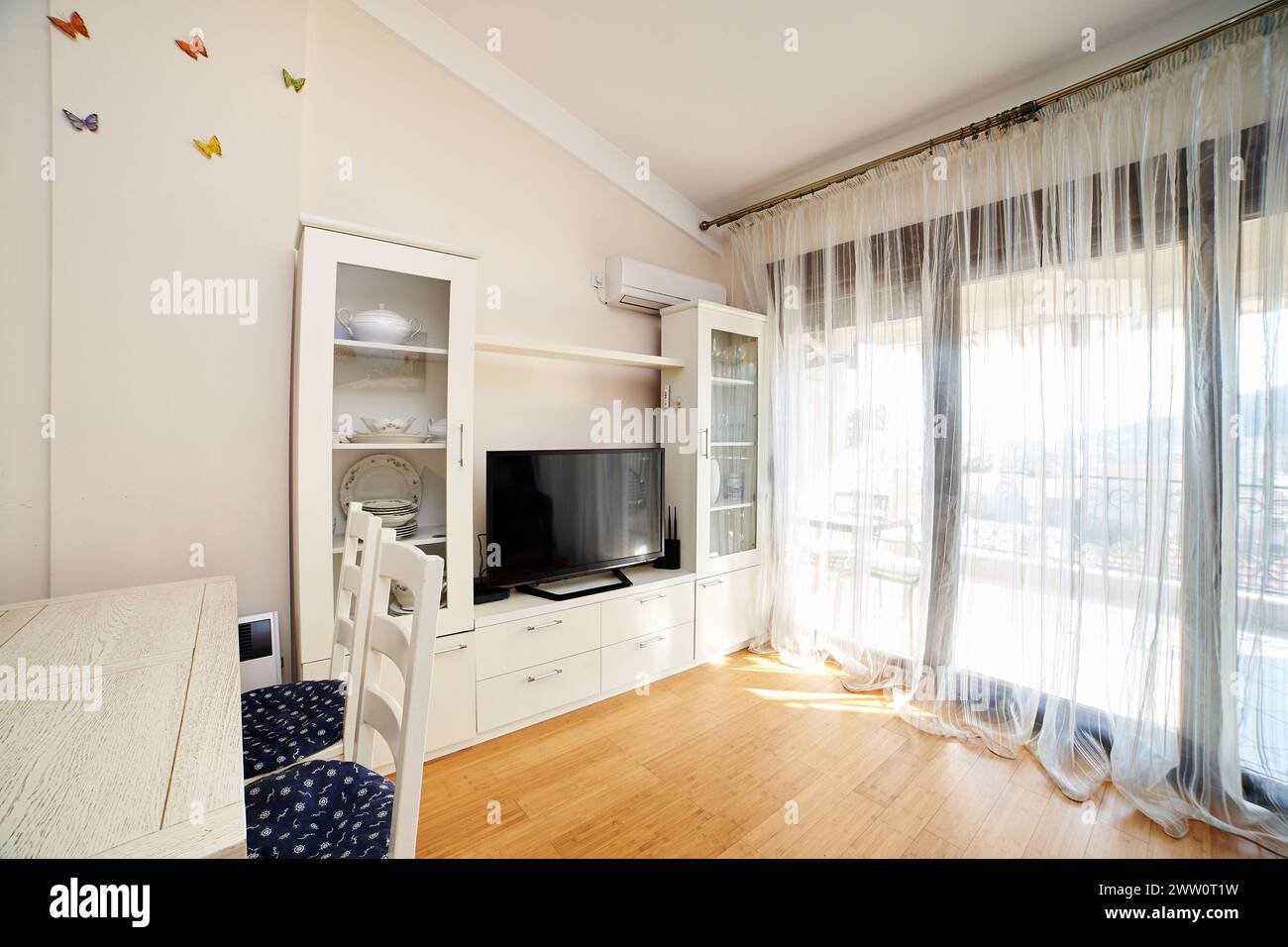 Beige living room with TV on the stand, table with chairs and cabinets ...