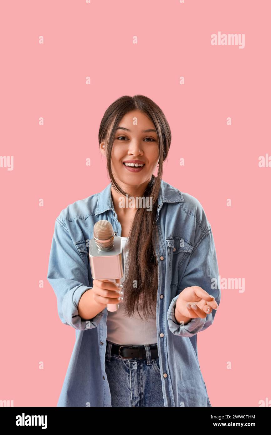 Female Asian journalist with microphone on pink background Stock Photo ...