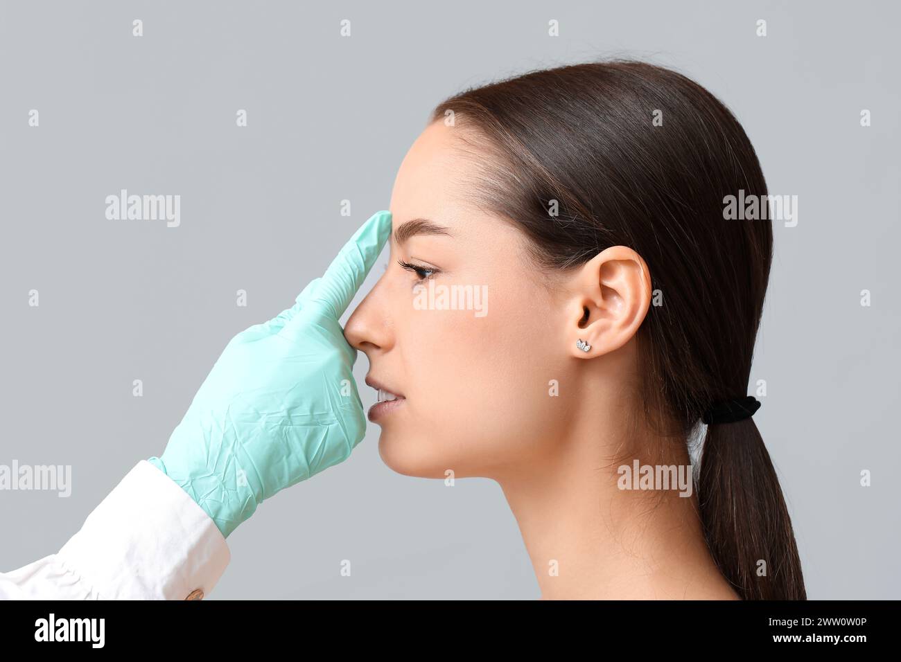 Doctor checking woman's nose before plastic surgery on white background ...