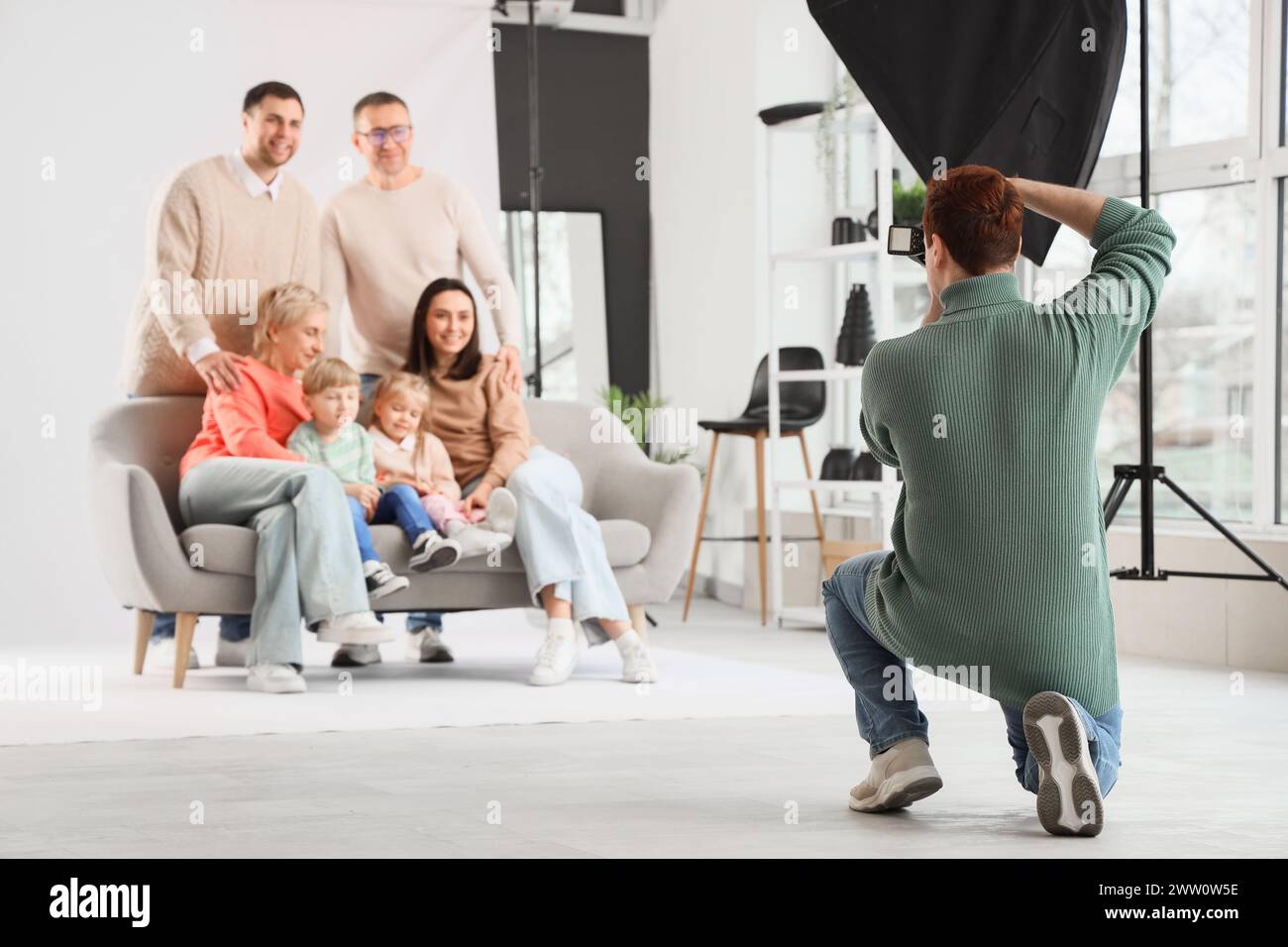 Male photographer taking picture of big family in studio, back view ...