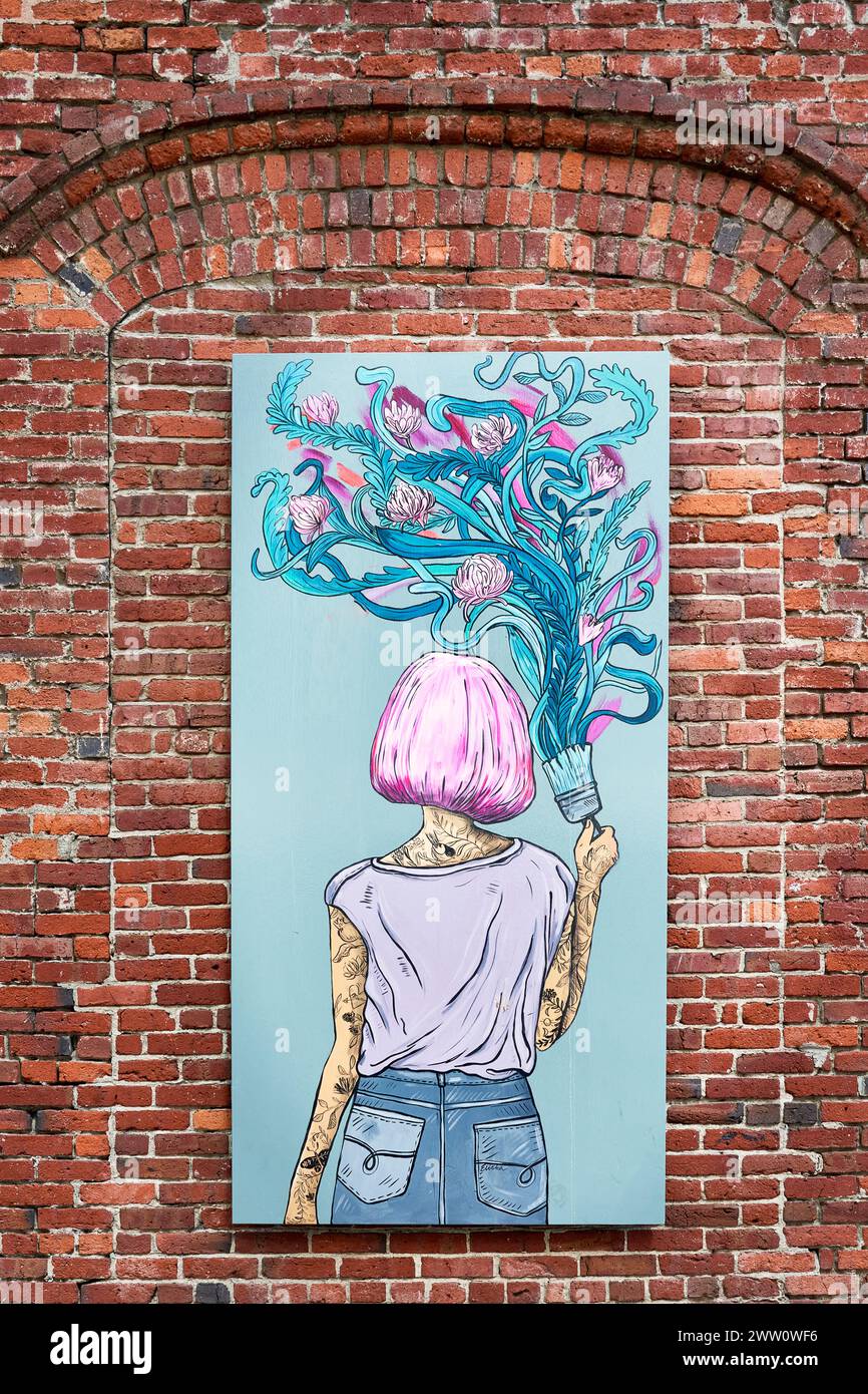 A mural of the back of a tattooed person with pink hair, wearing blue ...