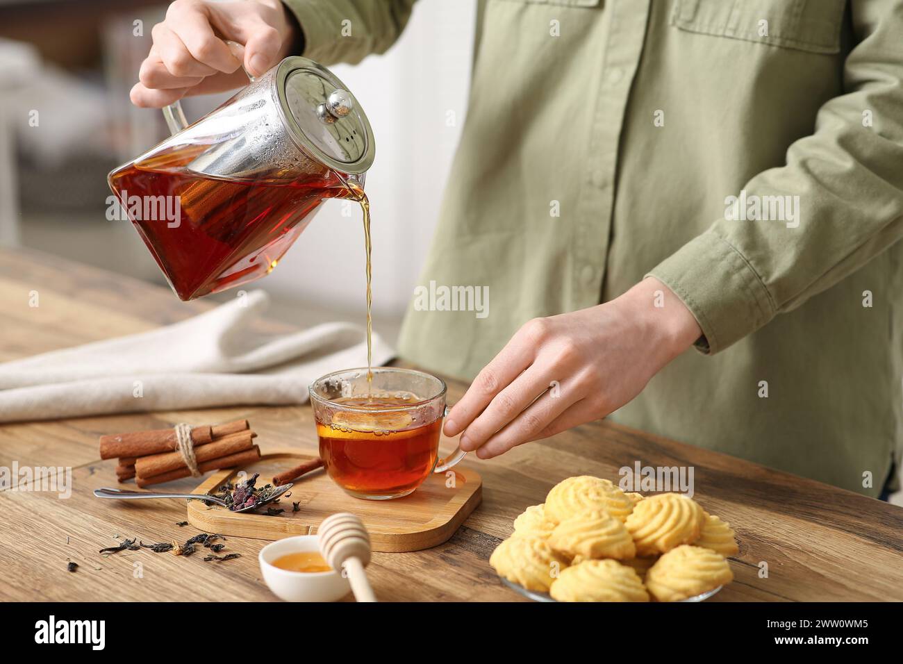 Young woman pouring black tea from teapot into cup in kitchen Stock ...