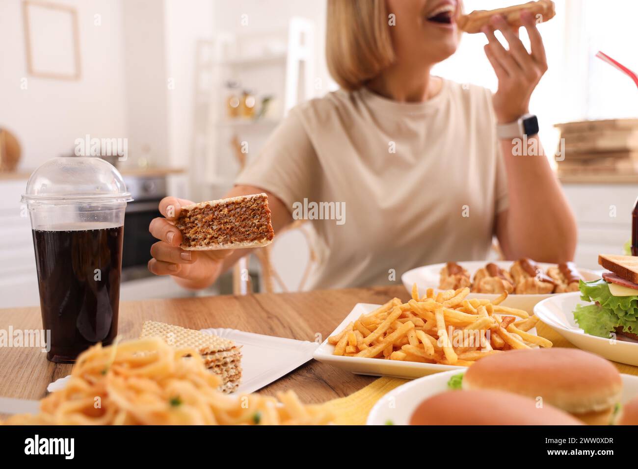 Beautiful woman at table full of unhealthy food in kitchen, closeup ...