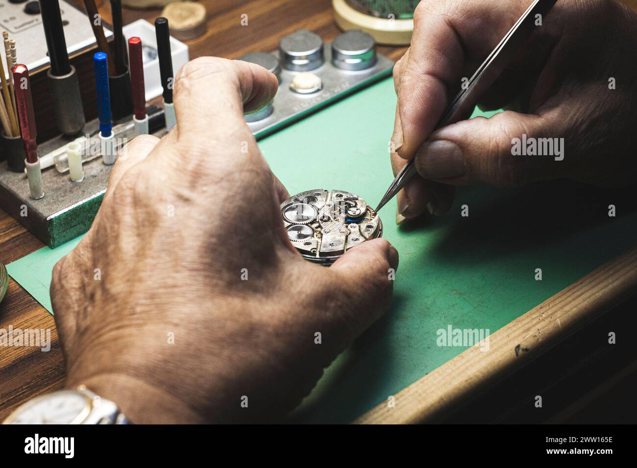 The hands of a watchmaker repairing a watch. They are manipulating a ...