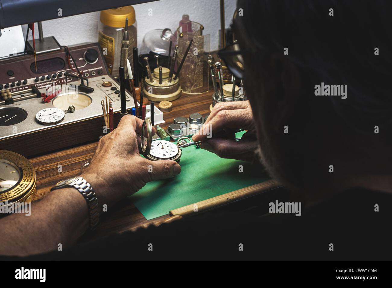 An over-the-shoulder view of a watchmaker repairing the machinery of a ...