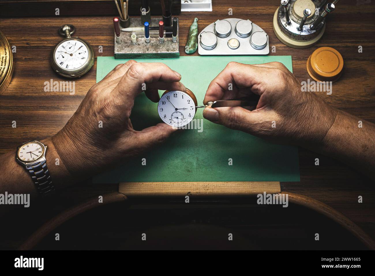 The expert hands of a watchmaker place the crown of a watch with ...