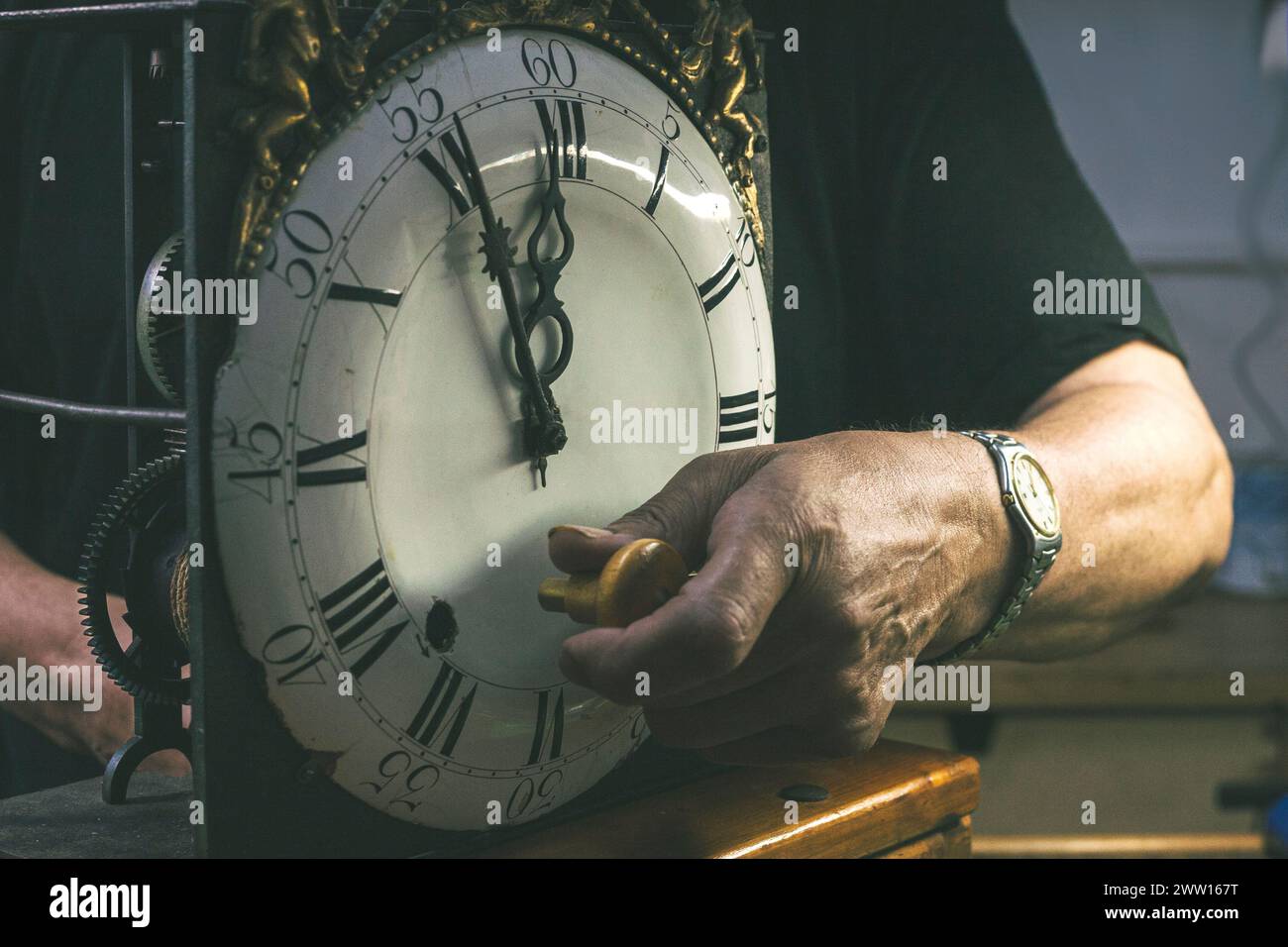 Detail of the hands of a watchmaker winding up a clockwork machine ...