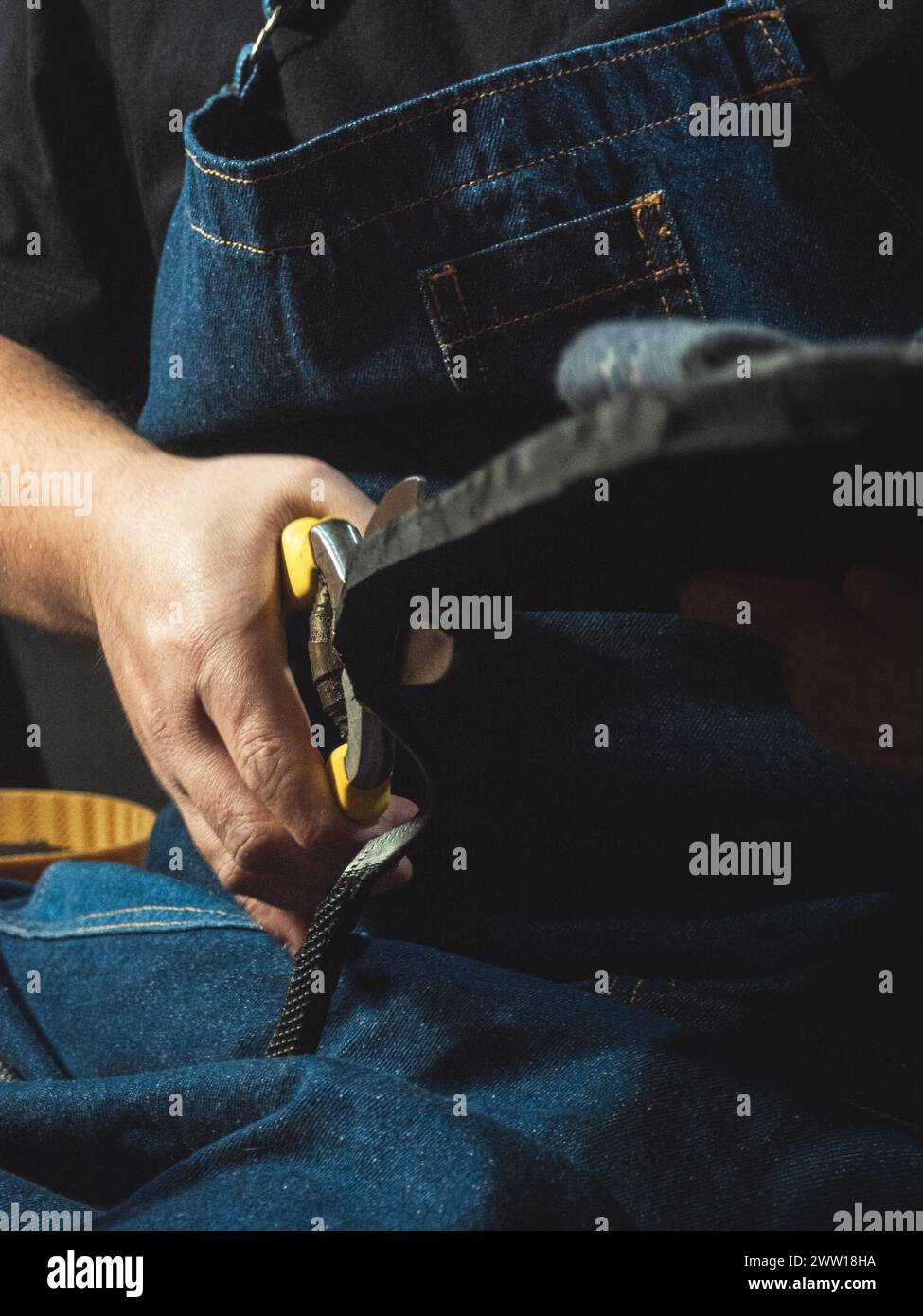 shoemaker's hands cutting with scissors the excess of the sole of the ...