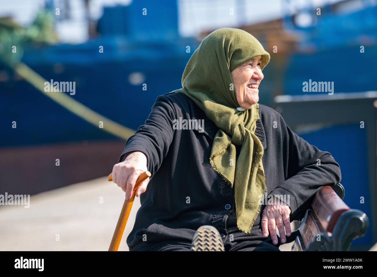 An elderly muslim lady with a walking stick watches the world go by ...