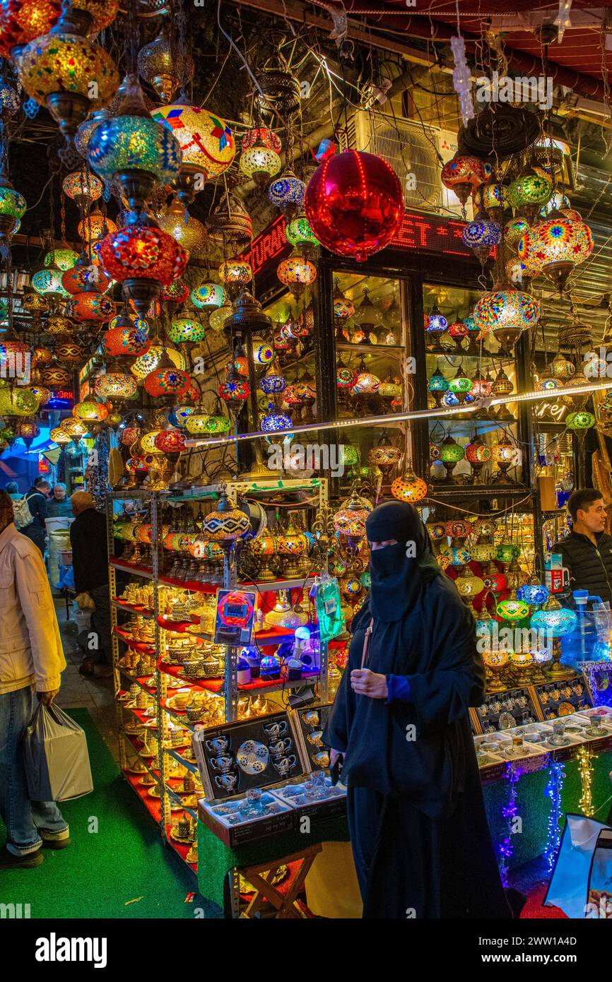 A lady in a burka walks past a light shop in the back streets of ...