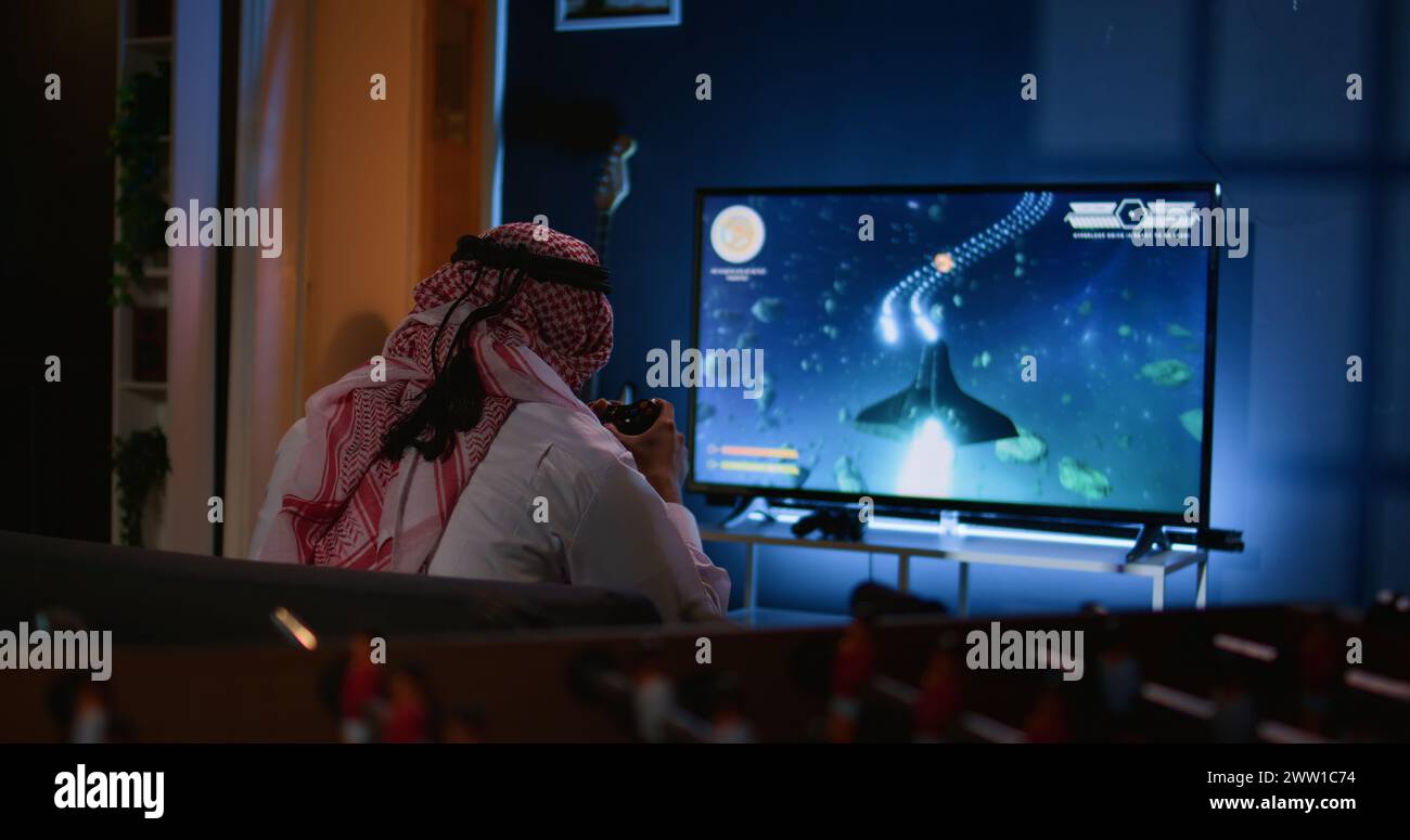 Muslim gamer plays intense classic arcade space shooter videogame ...