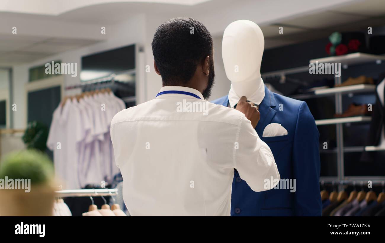 Employee tightening elegant blazer necktie on mannequin in luxurious ...
