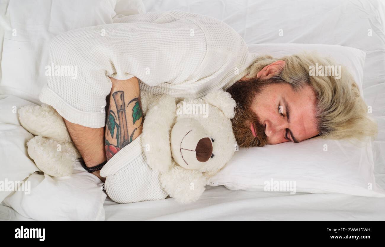 Bearded man sleeping at bedroom and hugging soft teddy bear. Handsome ...