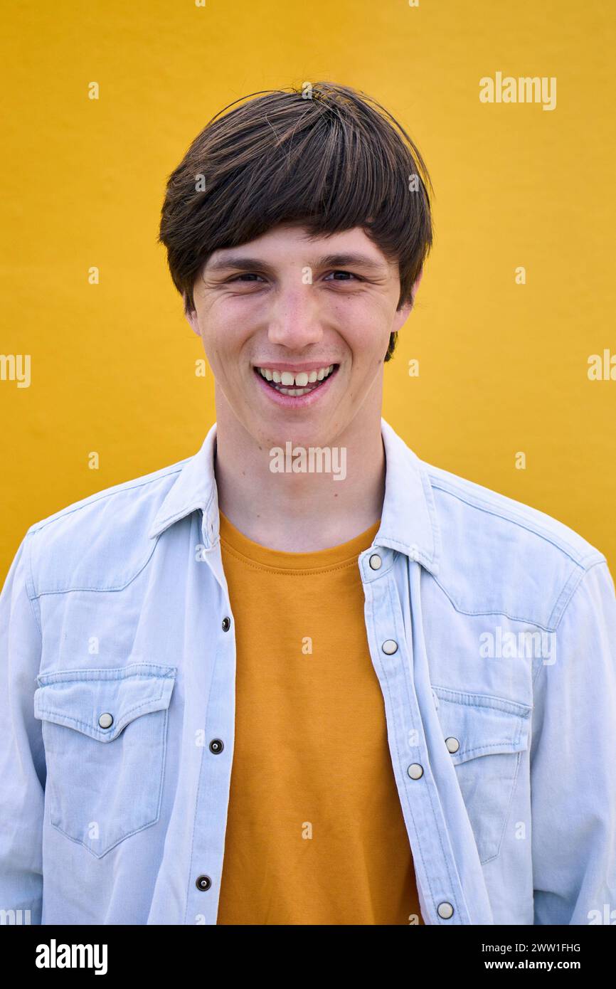 Smiling happy young Caucasian boy posing for portrait yellow isolated ...