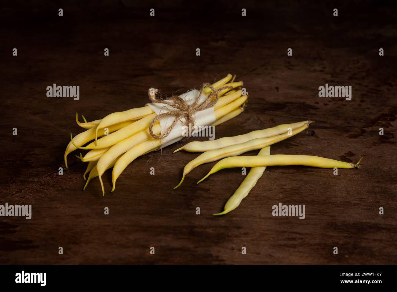 Bunch and several pods of raw yellow pods of haricot on wooden ...