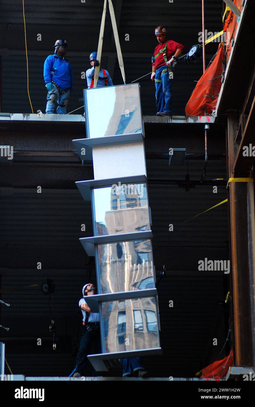 Construction Workers raise a panel of windows while making a skyscraper ...