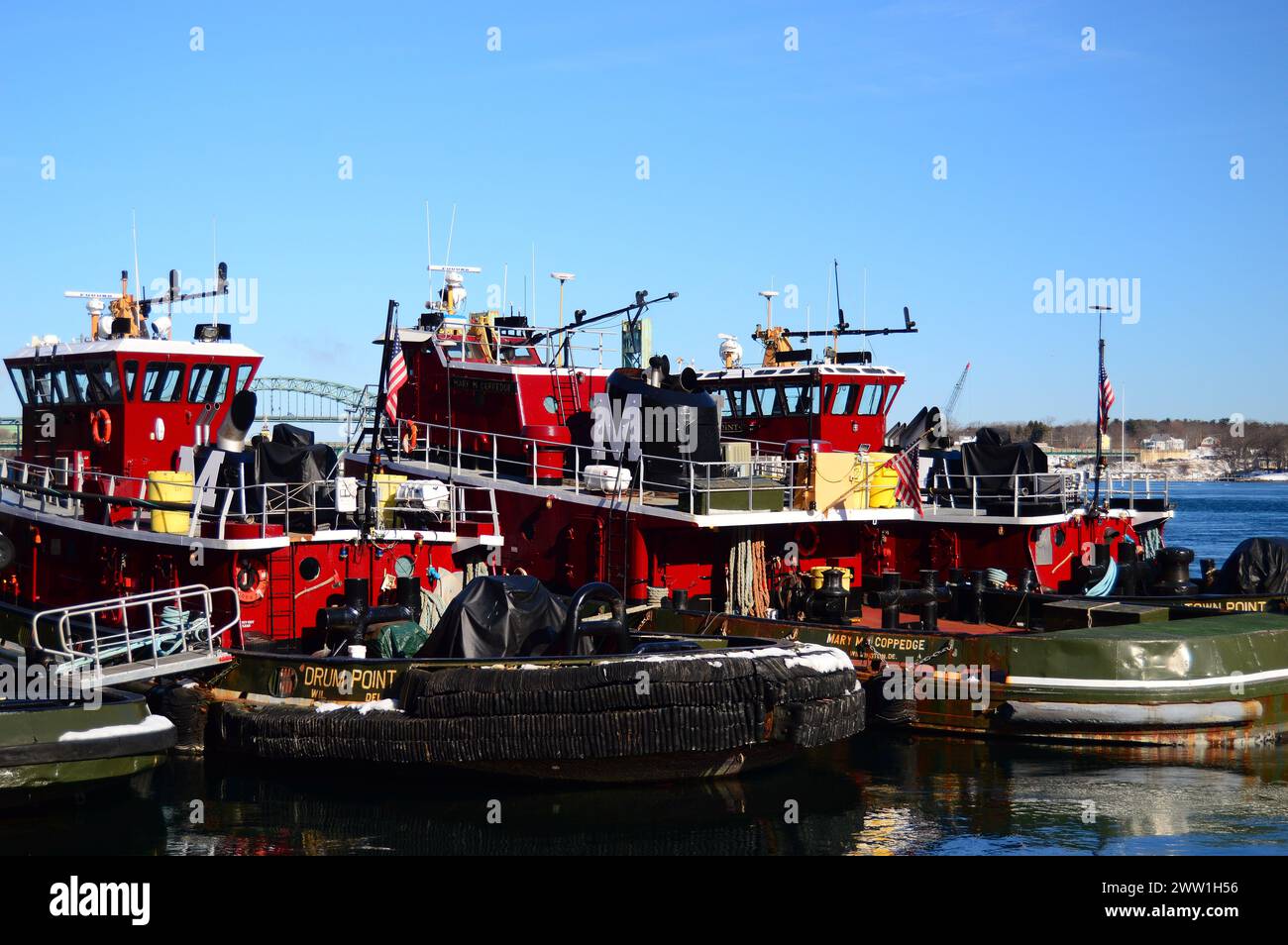 A fleet of red tugboats is prepares to lead the next cargo ship into ...