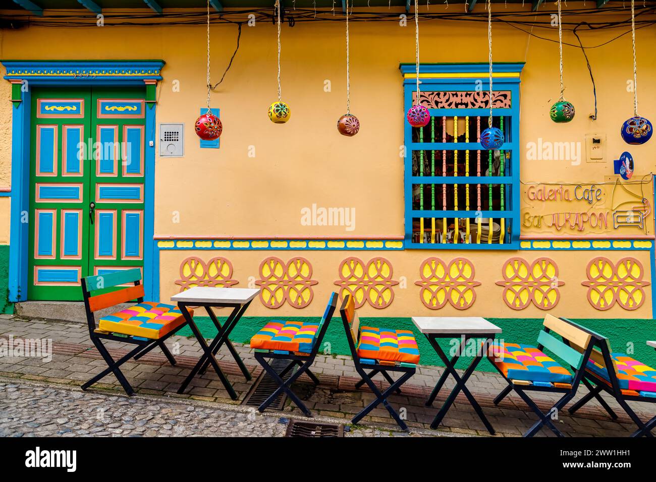 Seats and tables in front of a typical colorful house in Guatape ...