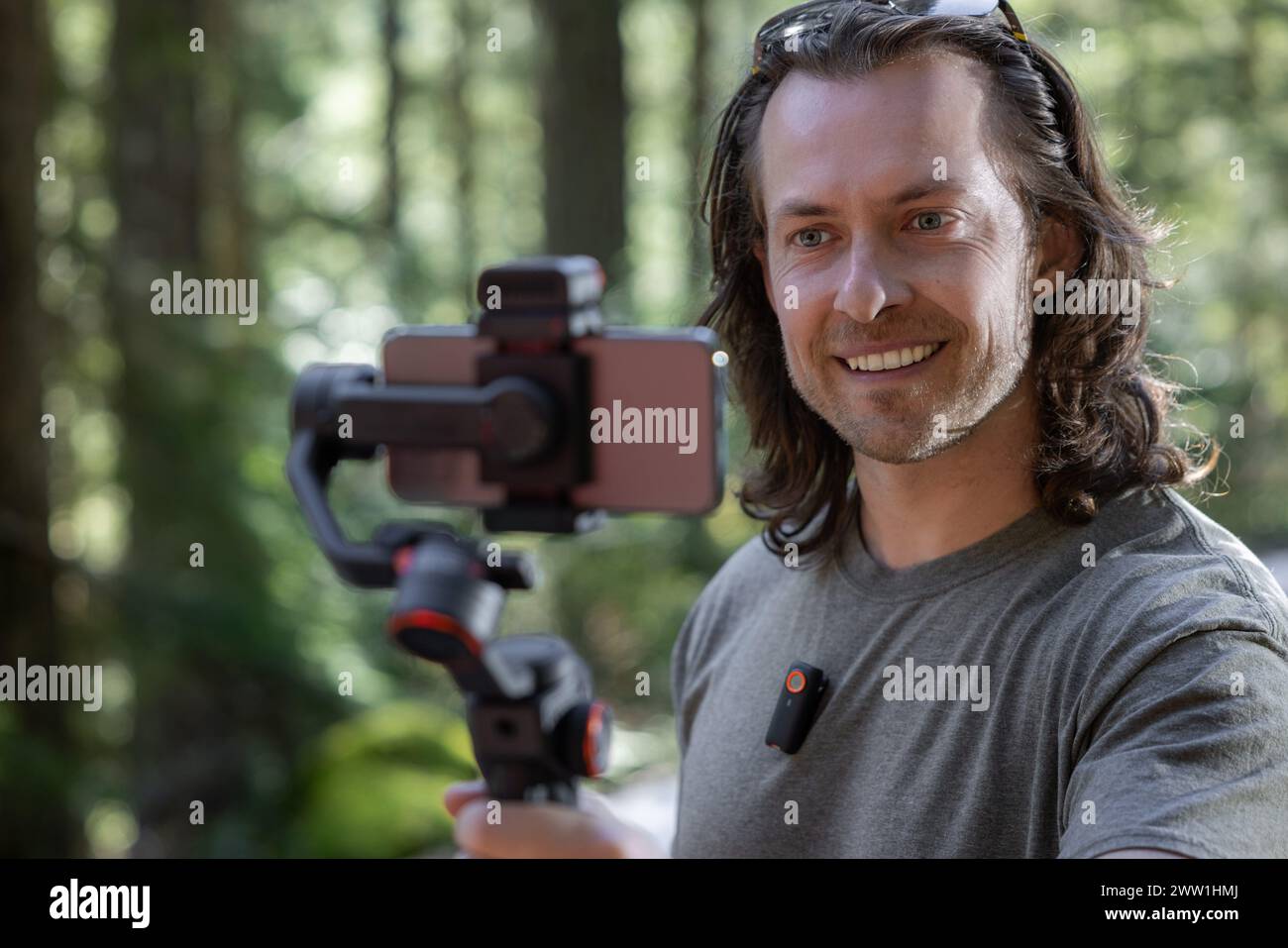 Content creator using. a phone gimbal to film in nature with a blurred ...