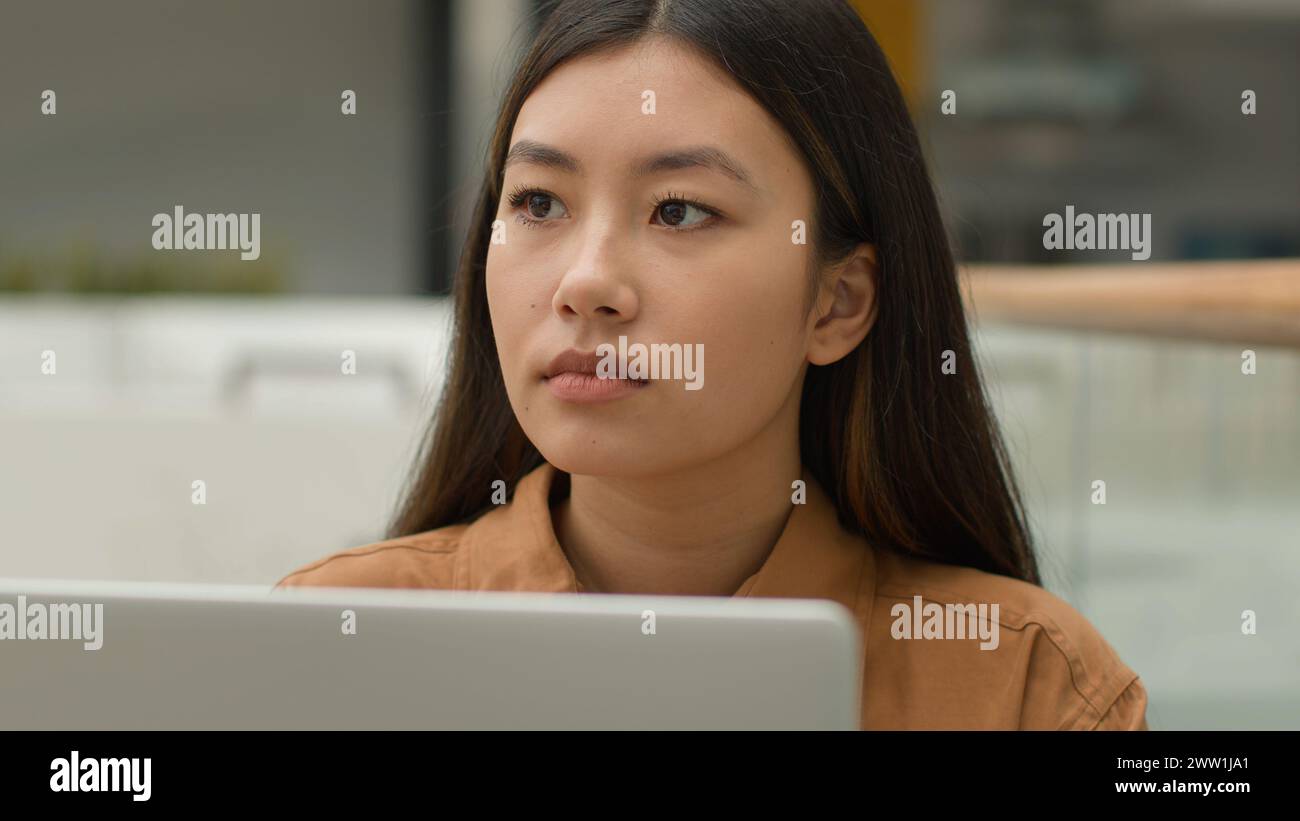 Close up pensive Asian woman working on laptop thinking solution chinese girl japanese korean ...