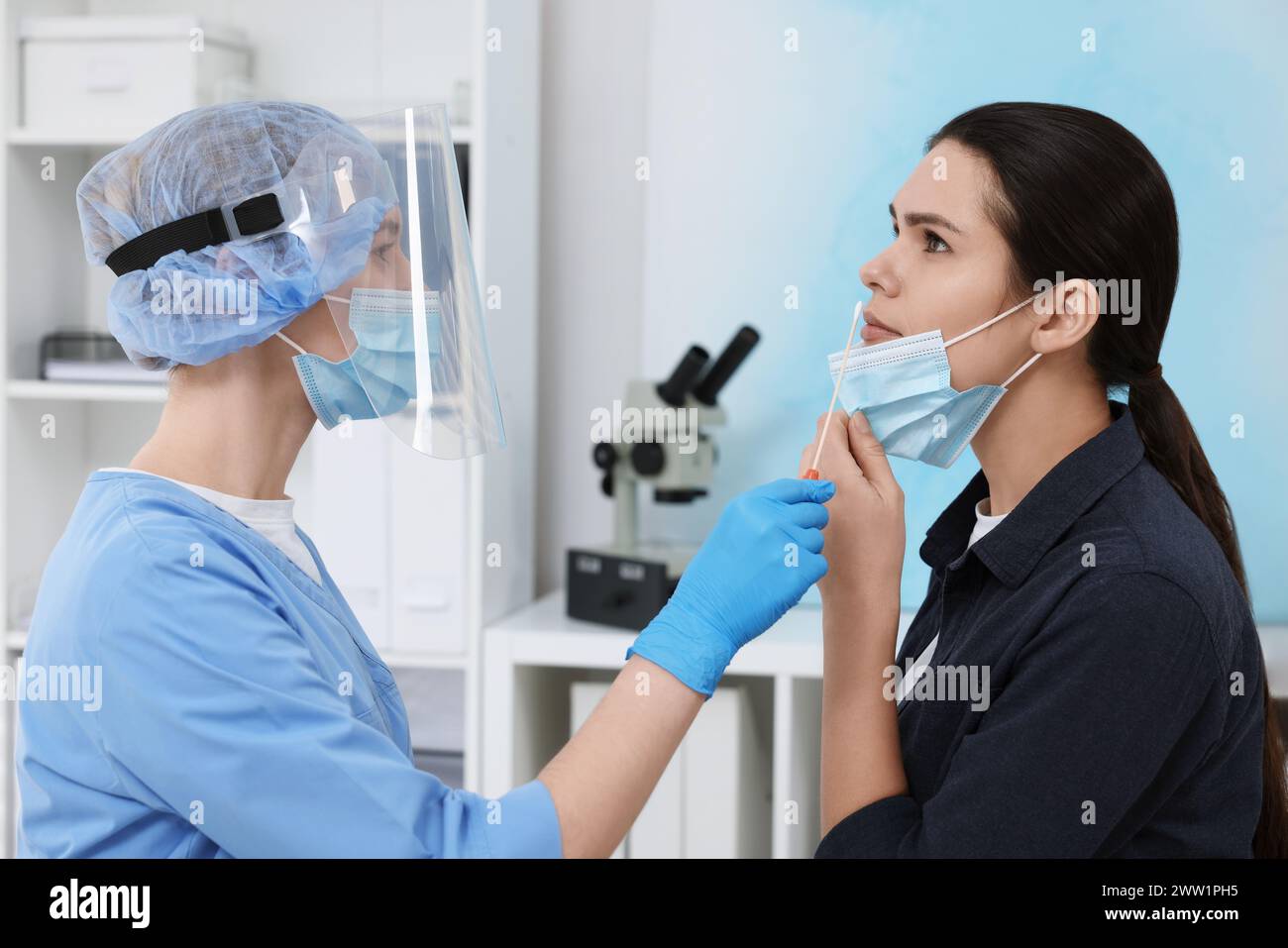 Laboratory testing. Doctor in uniform taking sample from patient's nose ...