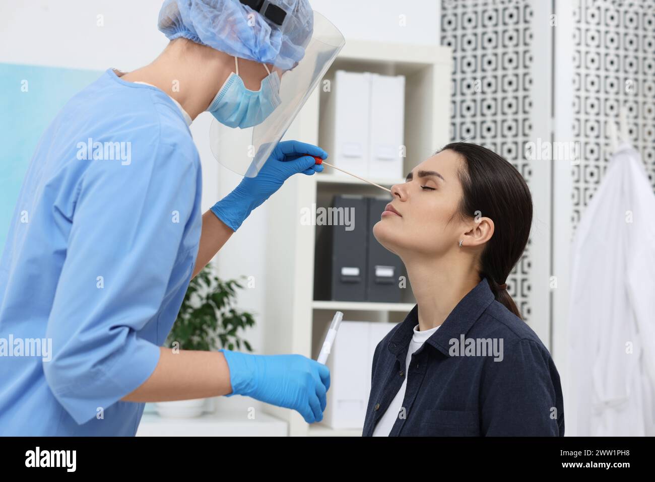 Laboratory testing. Doctor in uniform taking sample from patient's nose ...