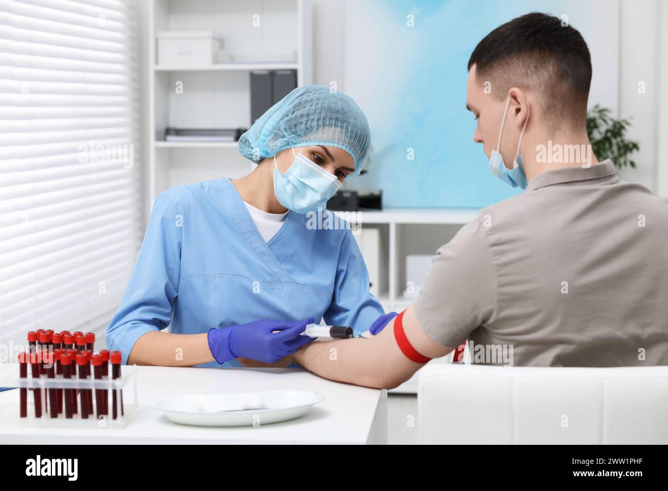 Laboratory testing. Doctor taking blood sample from patient at white ...