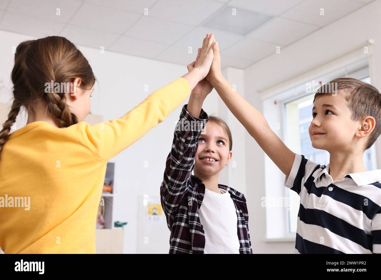 Happy children giving high five at school Stock Photo - Alamy