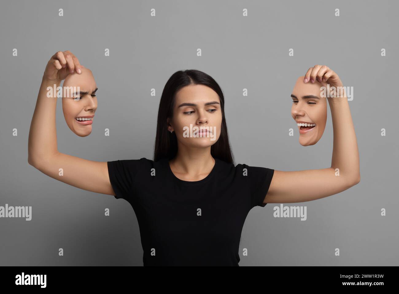 Woman holding masks with her face showing different emotions on grey ...