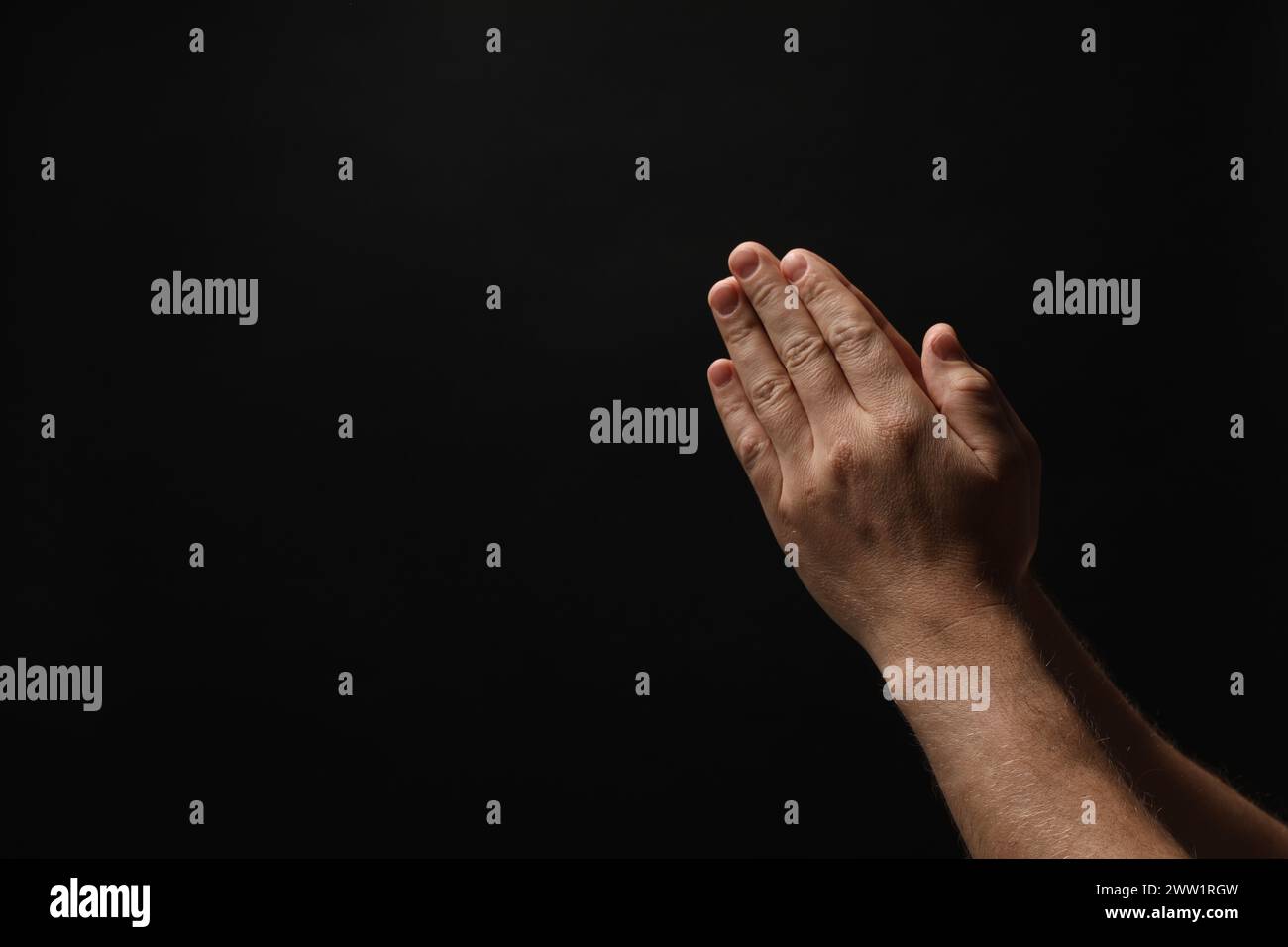 Religion. Christian man praying on black background, closeup. Space for ...