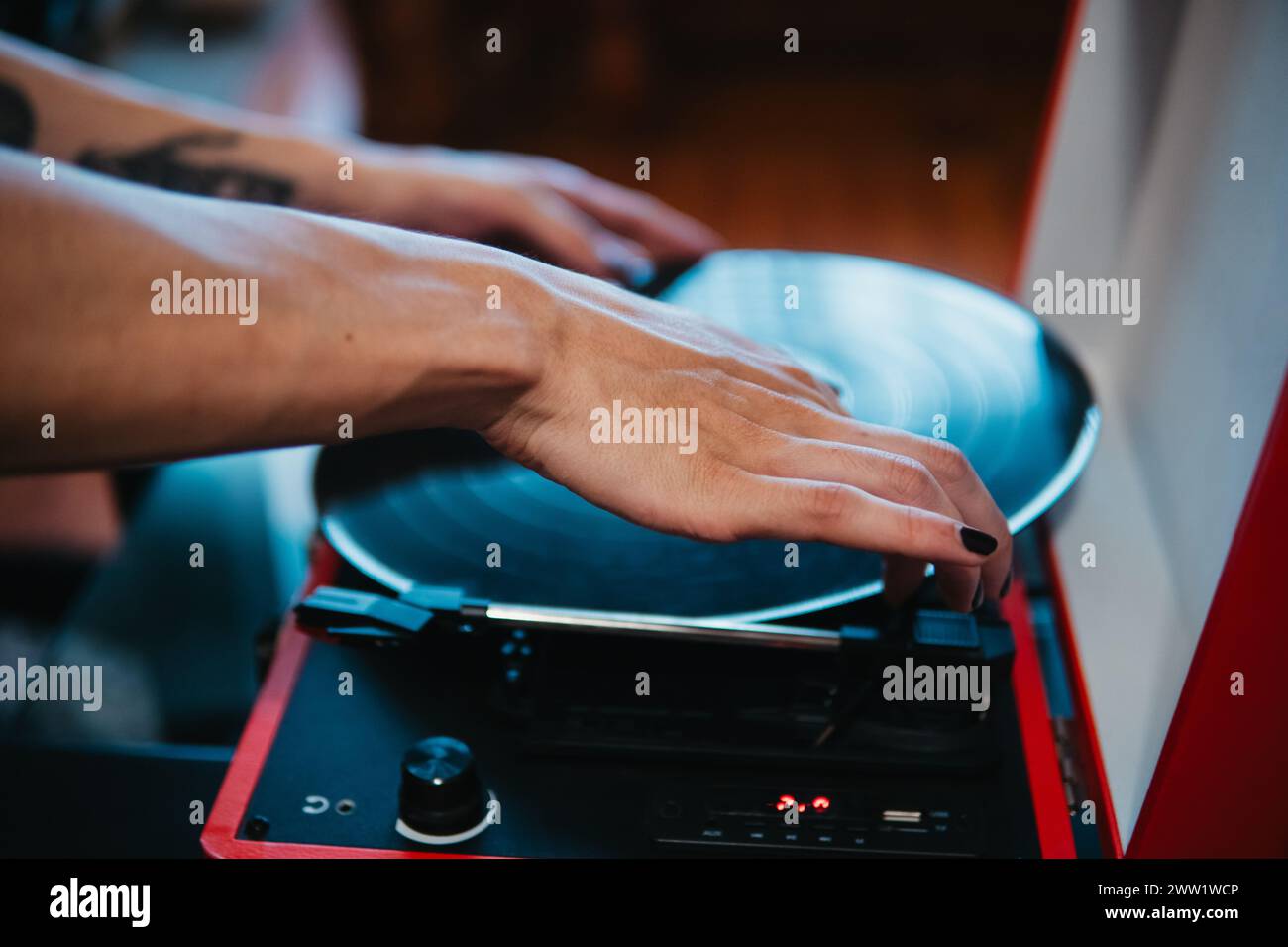 Hands placing a vinyl record on a red vintage turntable, a moment of ...
