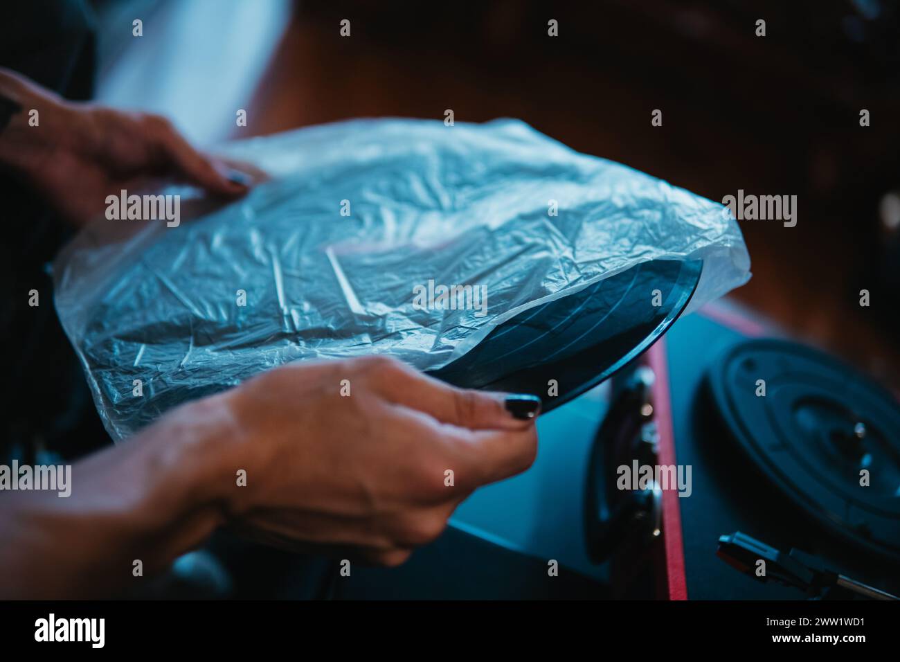 Close-up of a hand placing a vinyl record on a red portable turntable ...