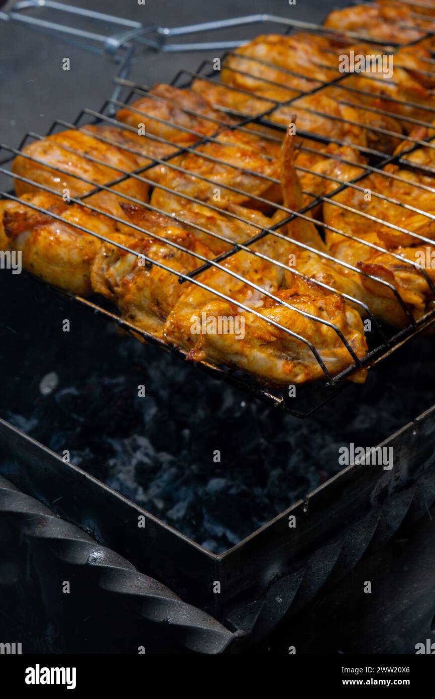 Delicious chicken frying on barbecue grill grate outdoor. Seasoning ...