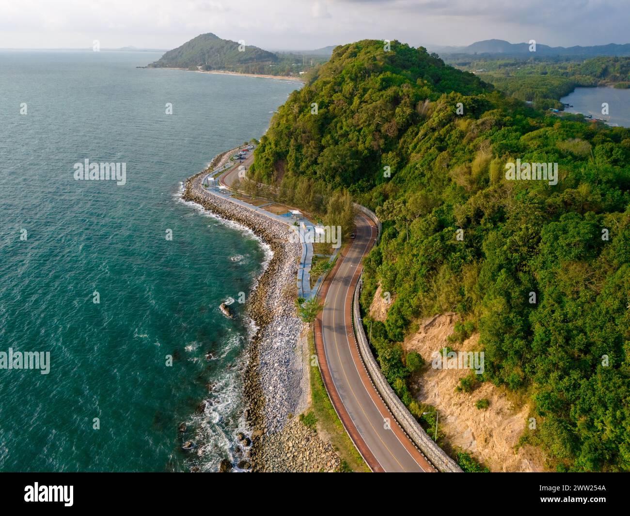 drone view at a curved road alongside the ocean beach road of Thailand ...