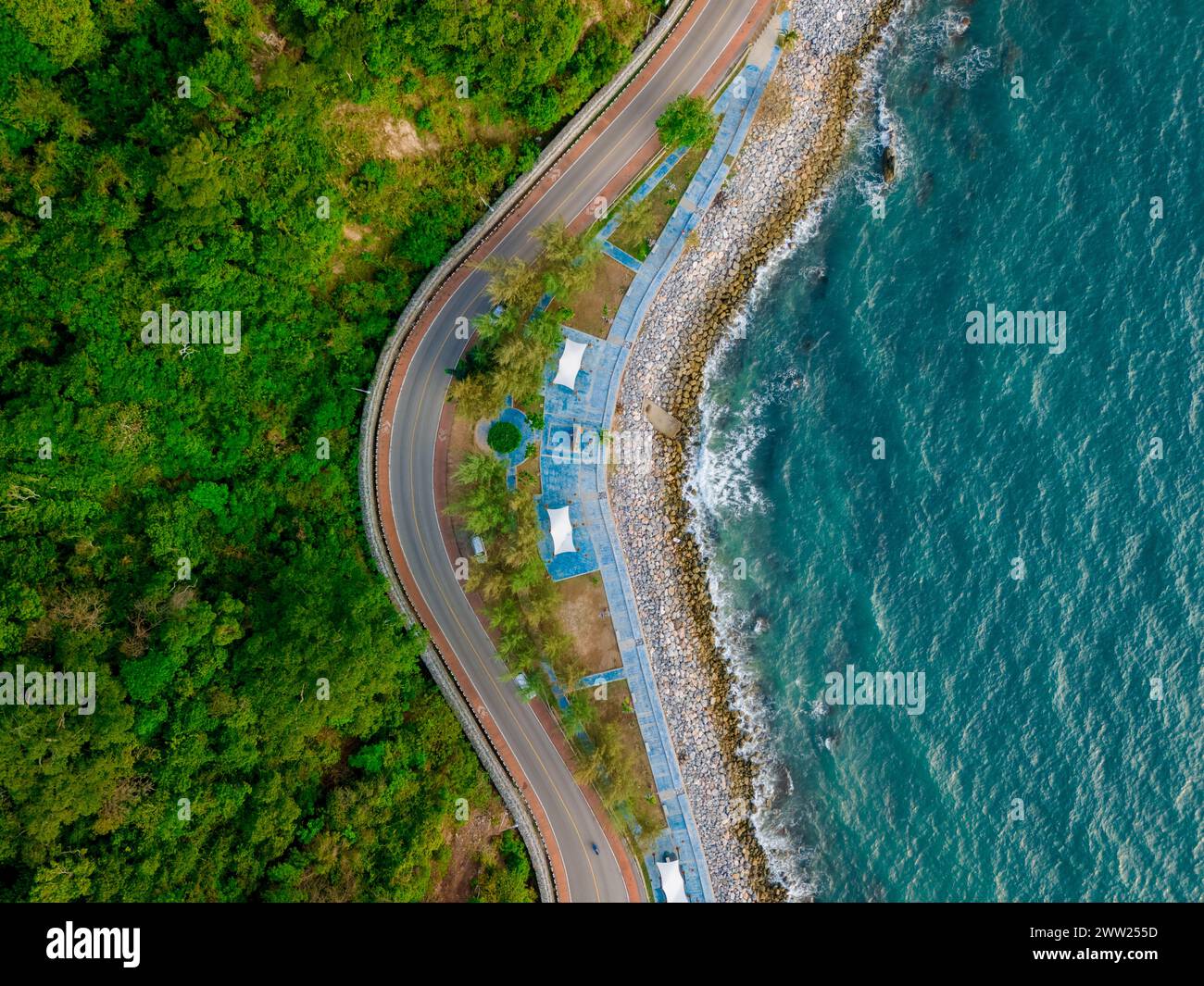 car driving on the curved road alongside the ocean beach road, top view ...