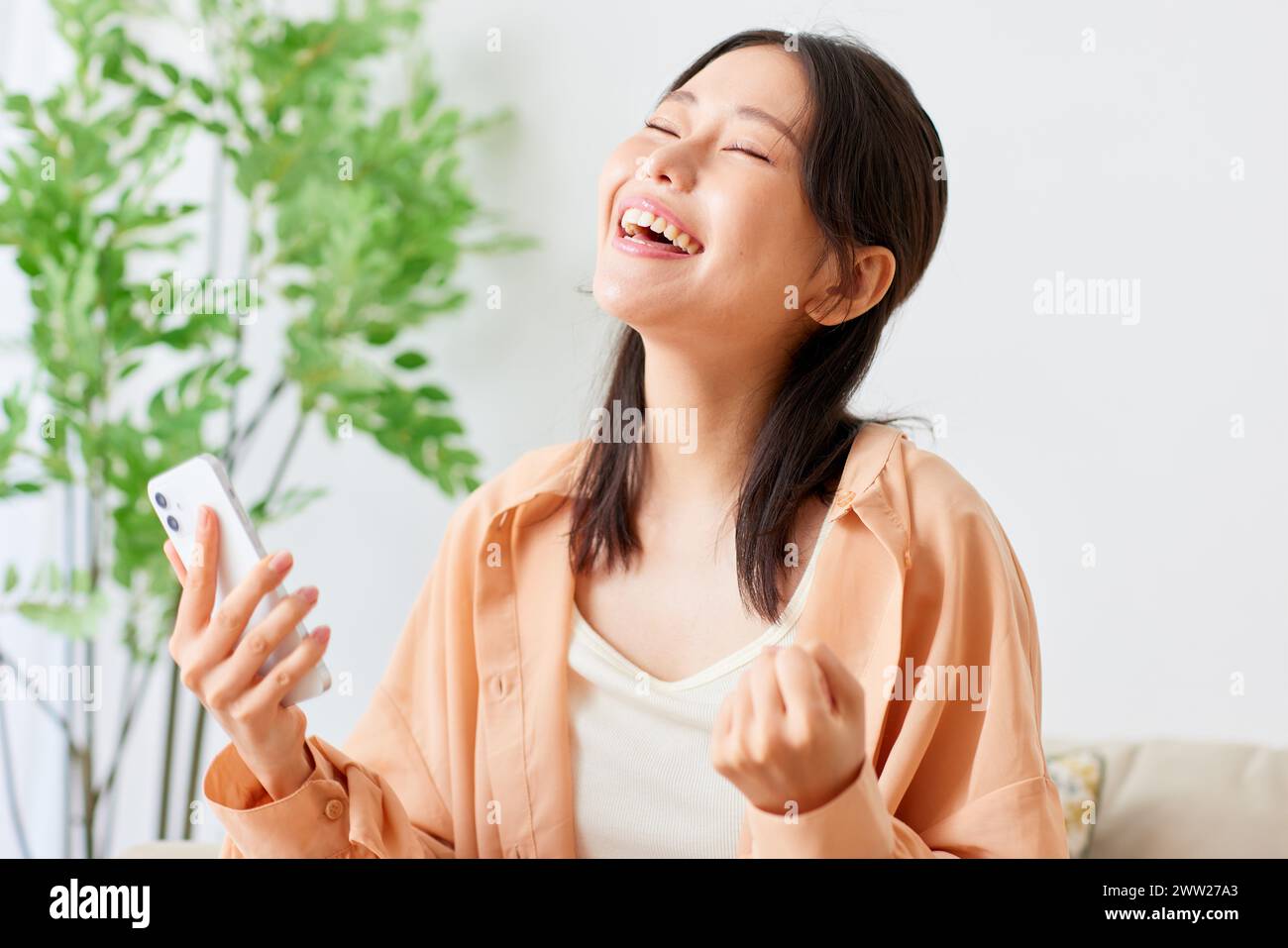Asian woman laughing while using her cell phone Stock Photo - Alamy
