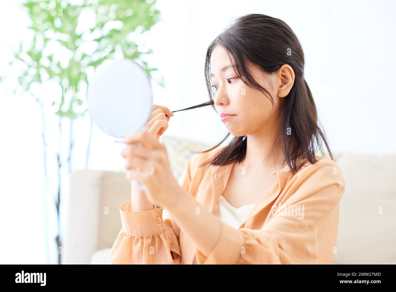 Woman checking hair mirror hi-res stock photography and images - Alamy