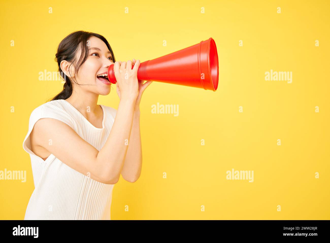 Asian woman shouting into a red megaphone Stock Photo - Alamy