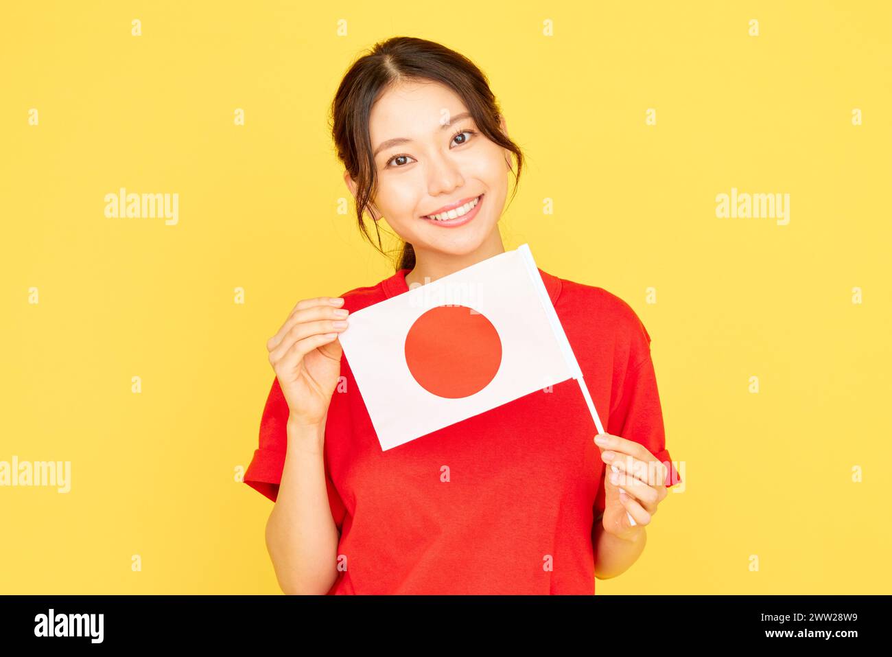 Asian woman holding Japan flag over yellow background Stock Photo - Alamy