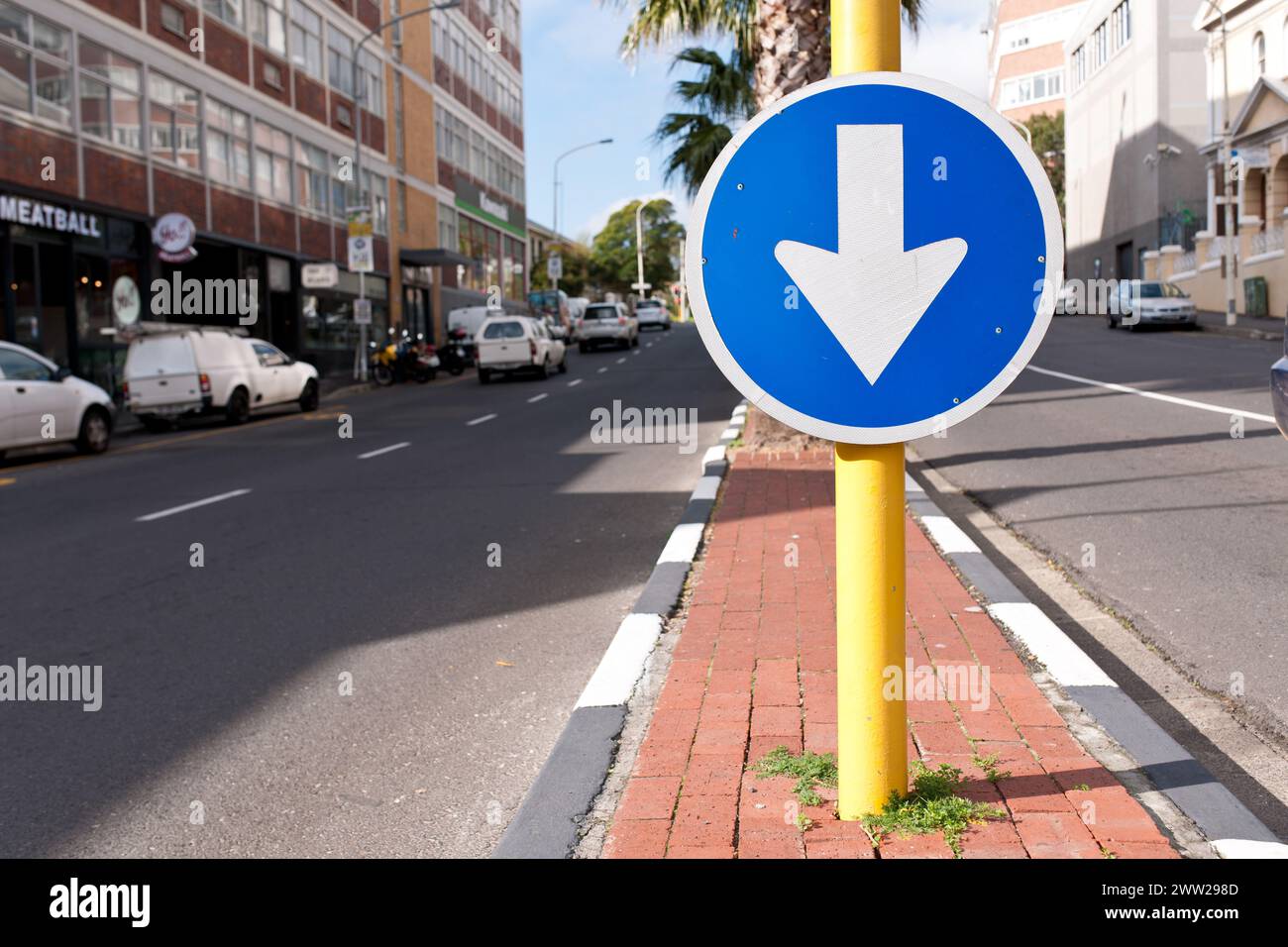 Road sign, blue arrow and signage in street for direction with ...