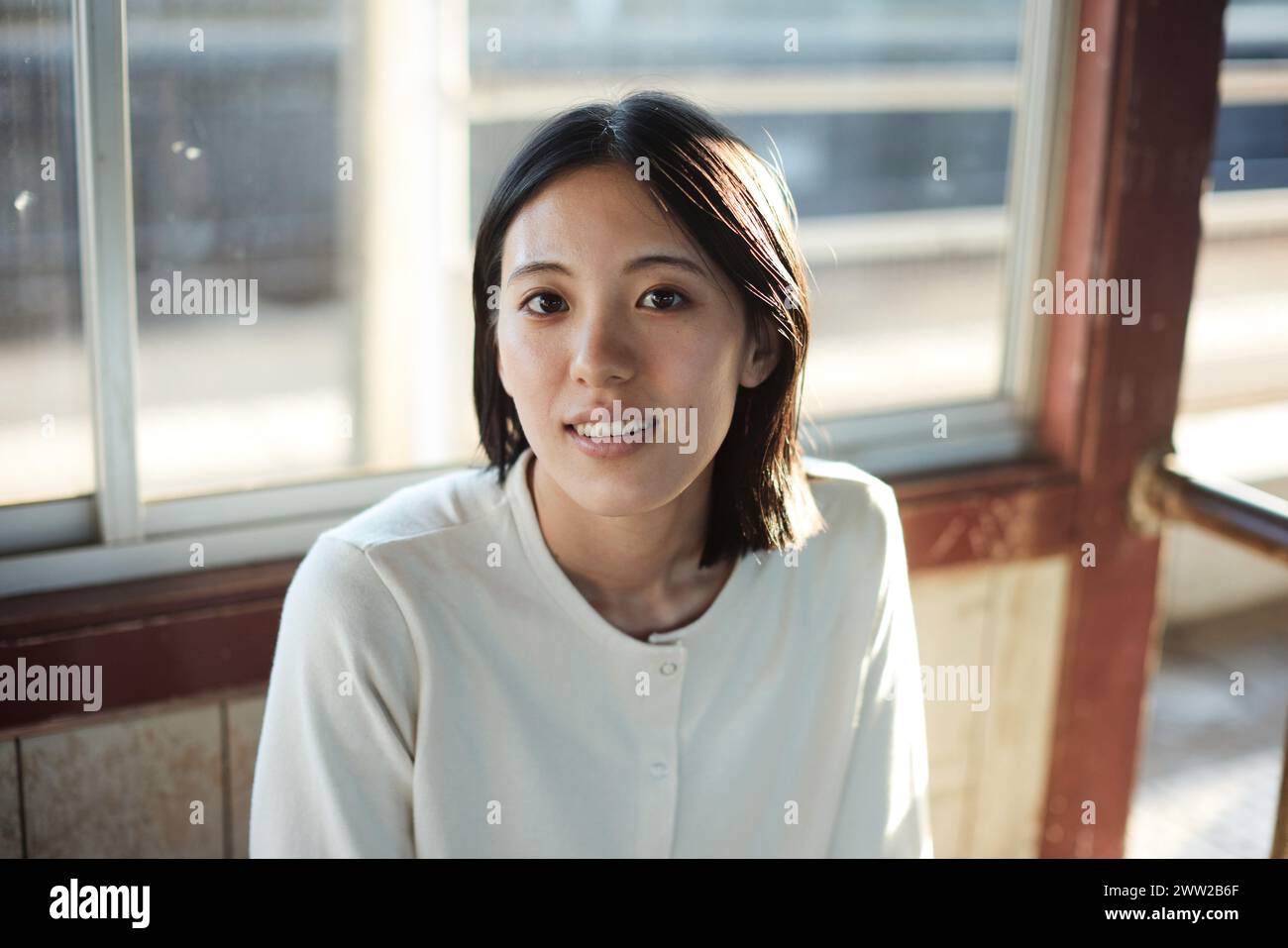 A woman sitting on a bench looking at the camera Stock Photo - Alamy